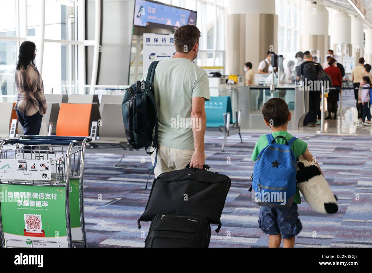 back view of father and son travelers with luggage and bag and face ...