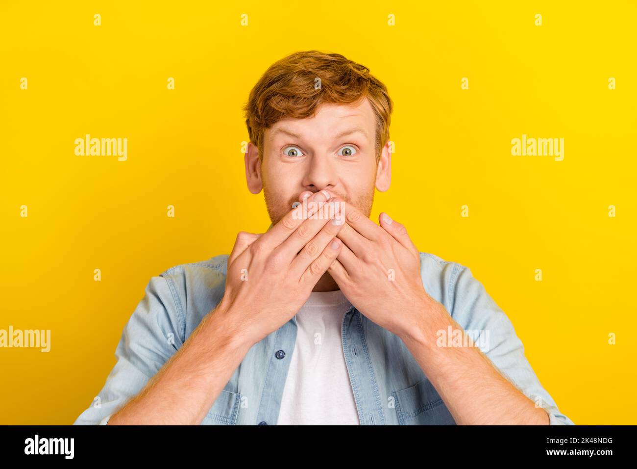 Photo of attractive impressed guy dressed denim shirt arms close mouth ...