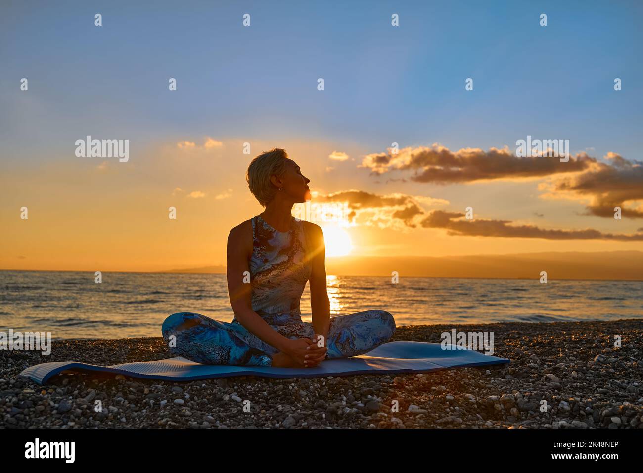 Young woman practicing yoga on the beach at sunrise. Harmony, wellbeing ...