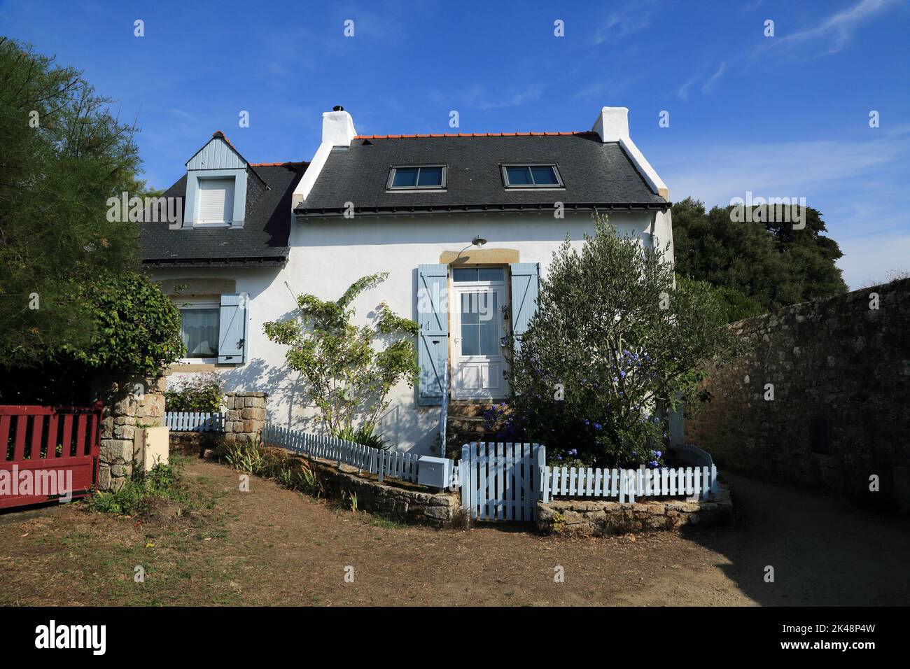 Whitewashed cottage with blue shutters on windows at Port Miquel on Ile ...
