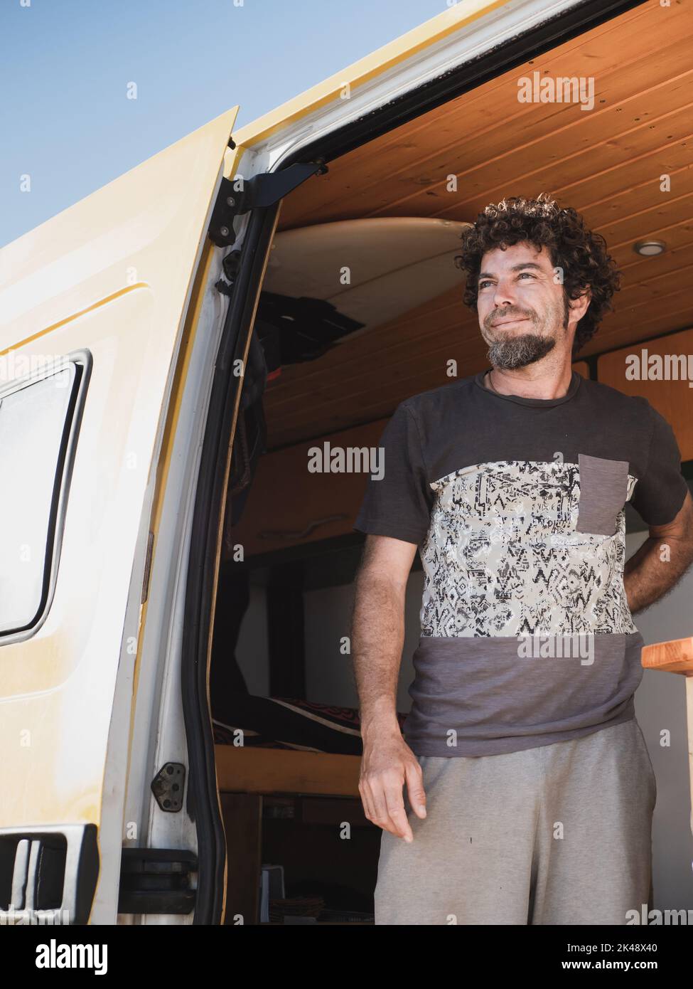 Caucasian man inside his camper van looking outside in the morning ...
