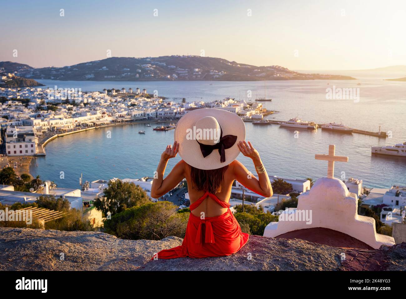 A elegant tourist woman in a red dress enjoys the view over the city of ...