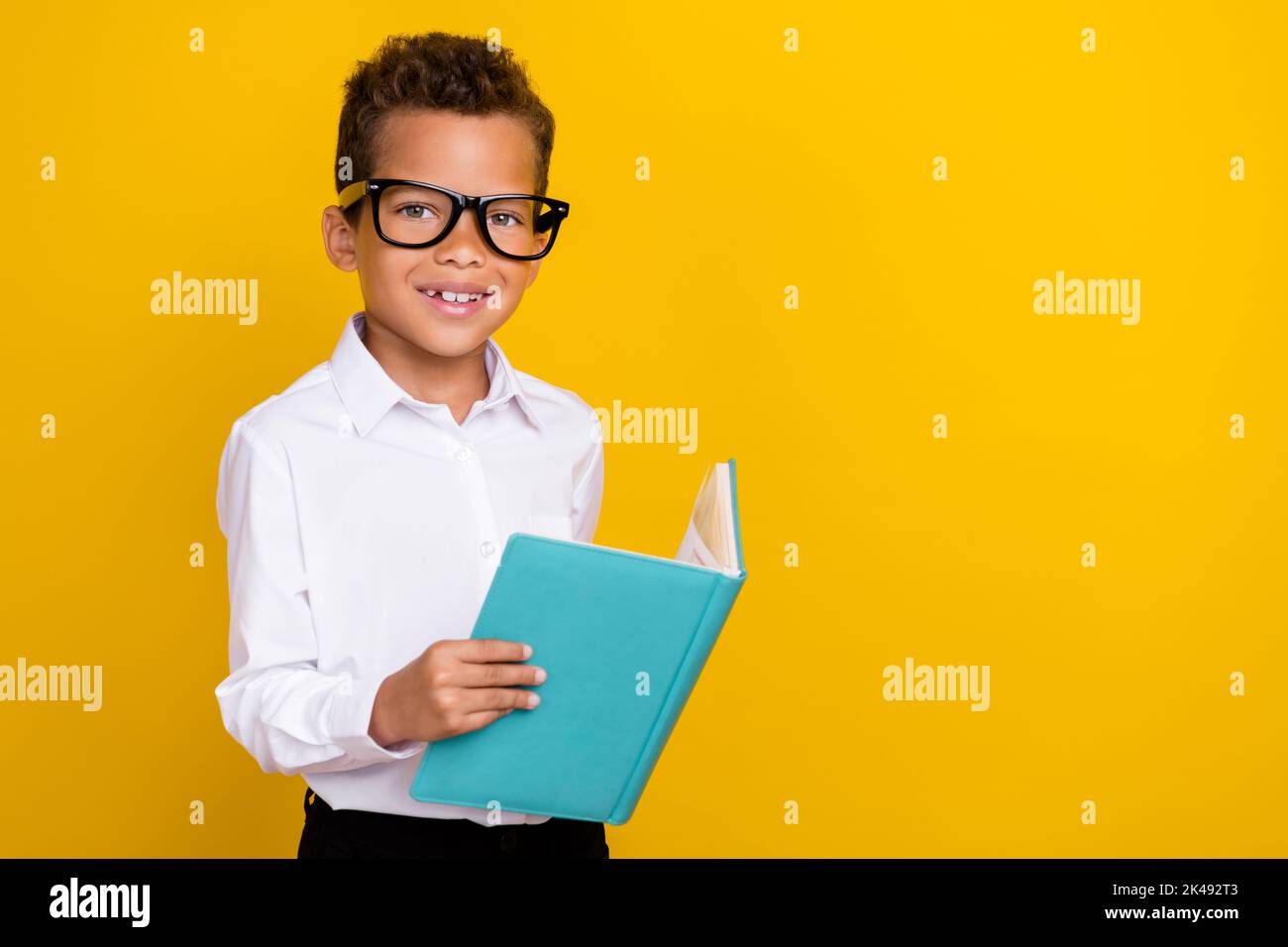 Photo of clever cute boy learner wear eyeglasses hold copybook read ...