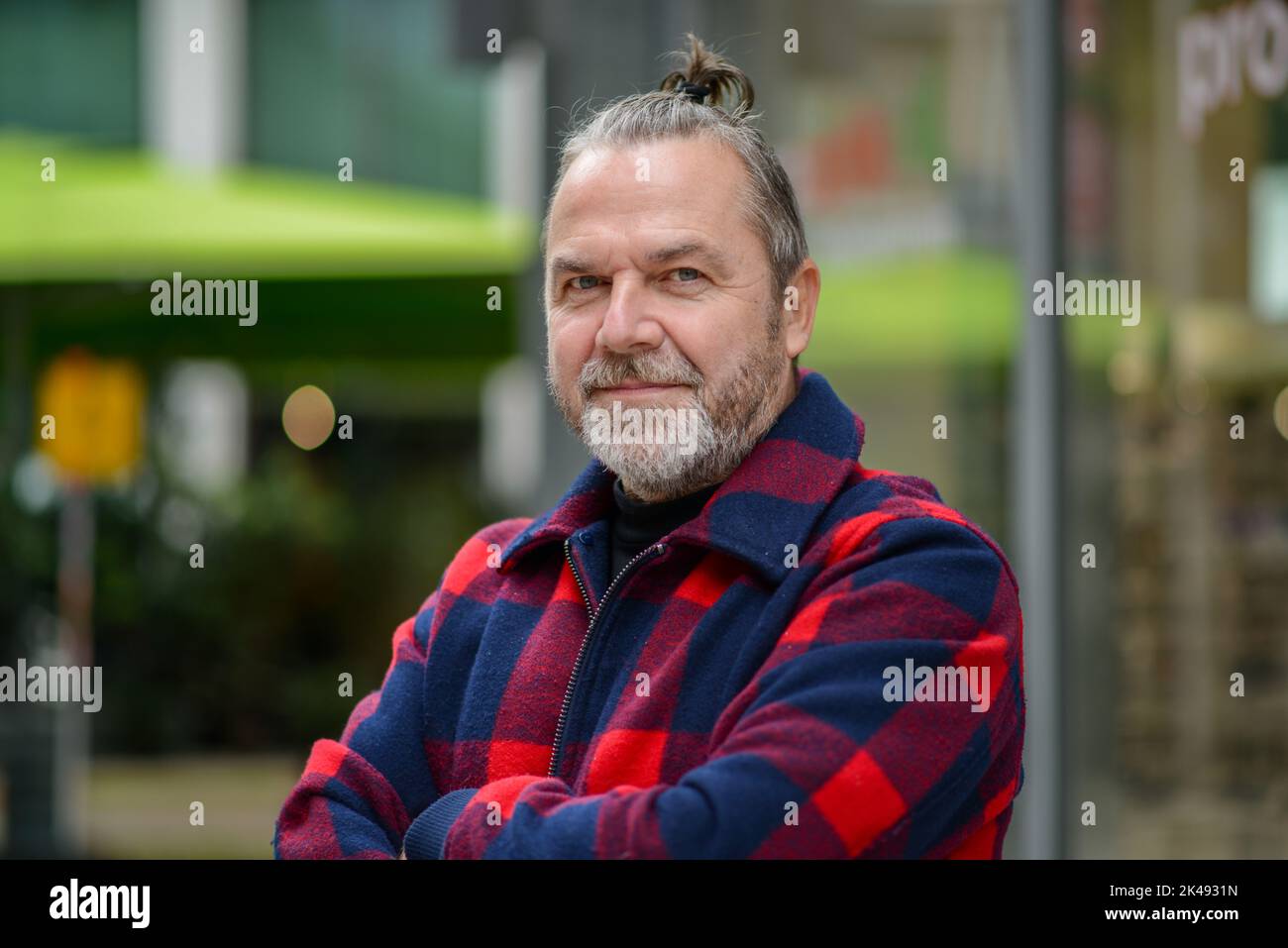 Sideview middle aged man with a messy bun in a red and blue jacket in ...