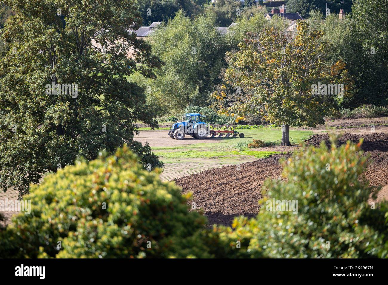 Blue tractor ploughing field out in countryside farm setting for ...