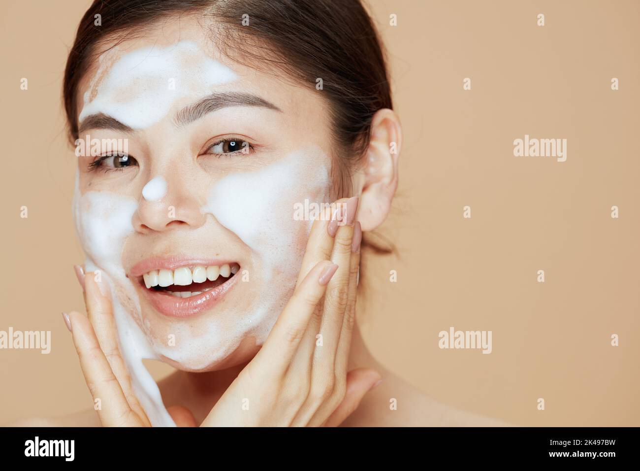 Portrait of modern woman washing face against beige background Stock ...