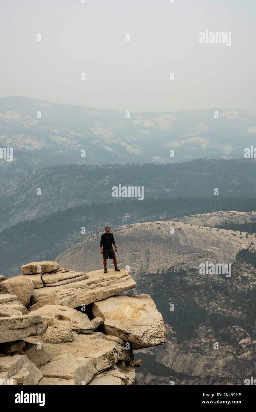Man Poses On The Edge of Half Dome on smoky day in Yosemite Stock Photo ...