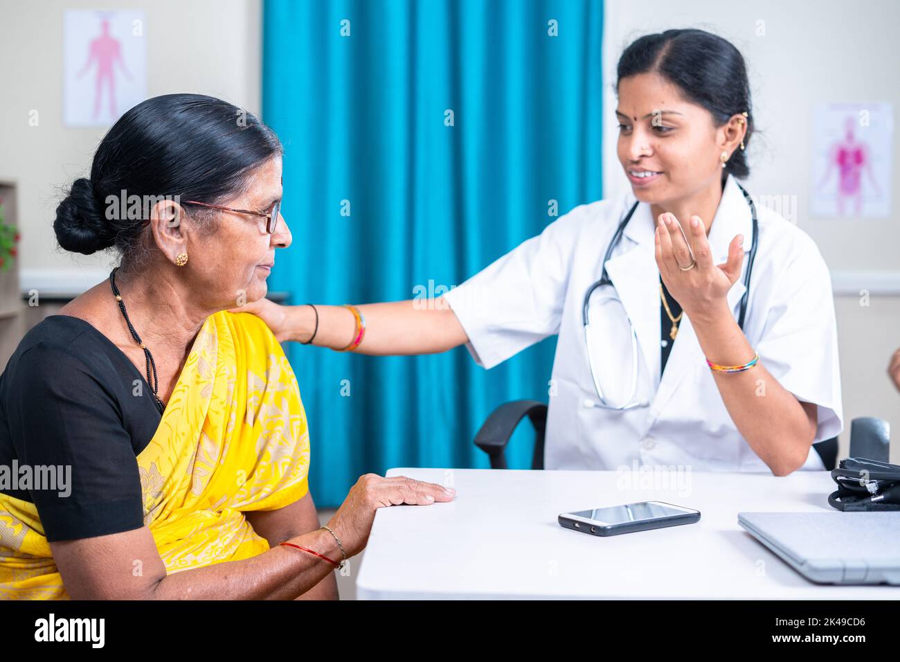 senior indian docter sugesting healthy tips or counsulting patient at ...