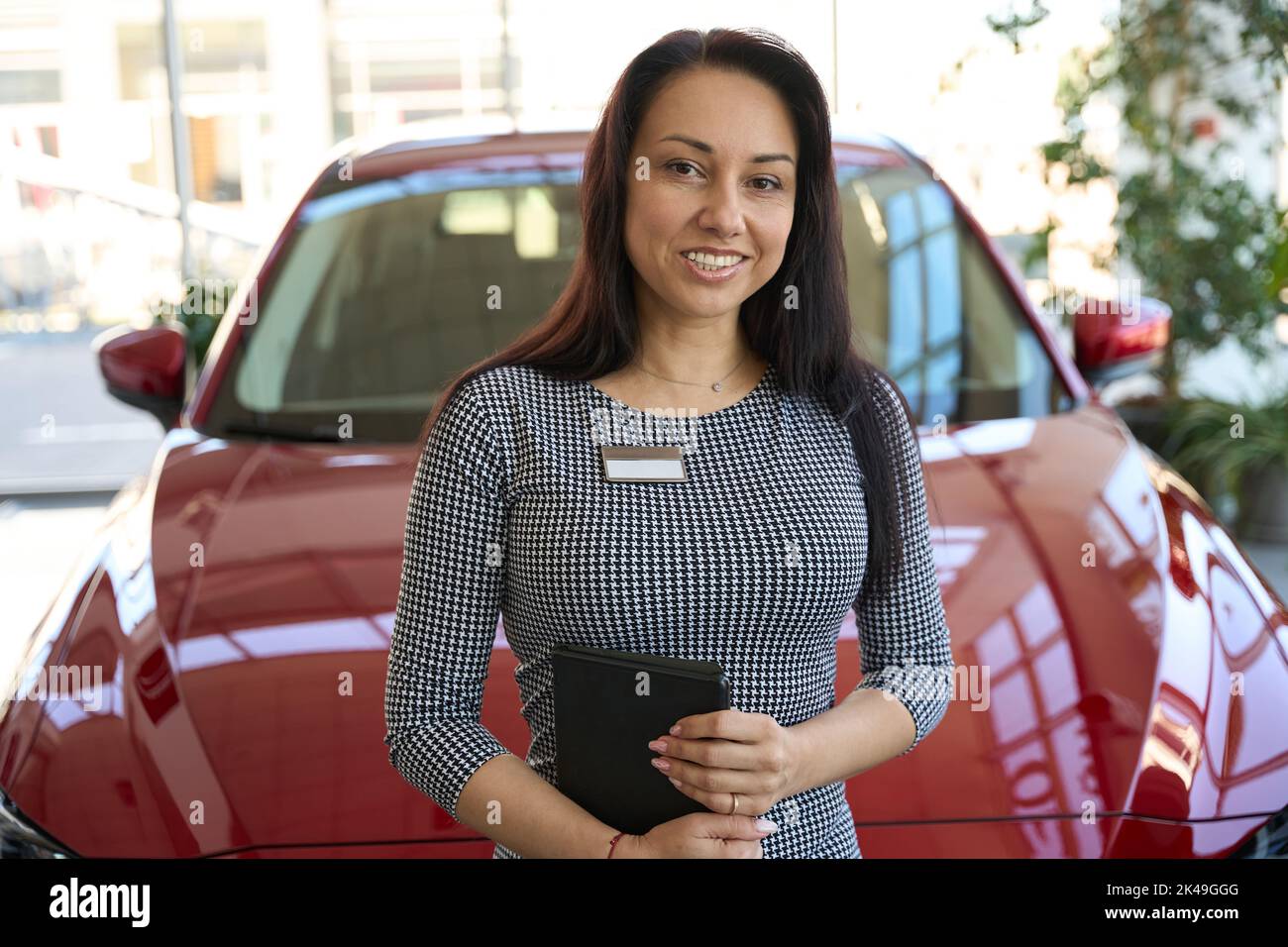 Pretty car dealership manager on the background of red car Stock Photo ...
