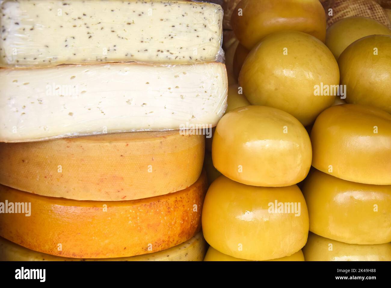 Cheese heads of different colors and sizes are stacked on counter. Fair ...
