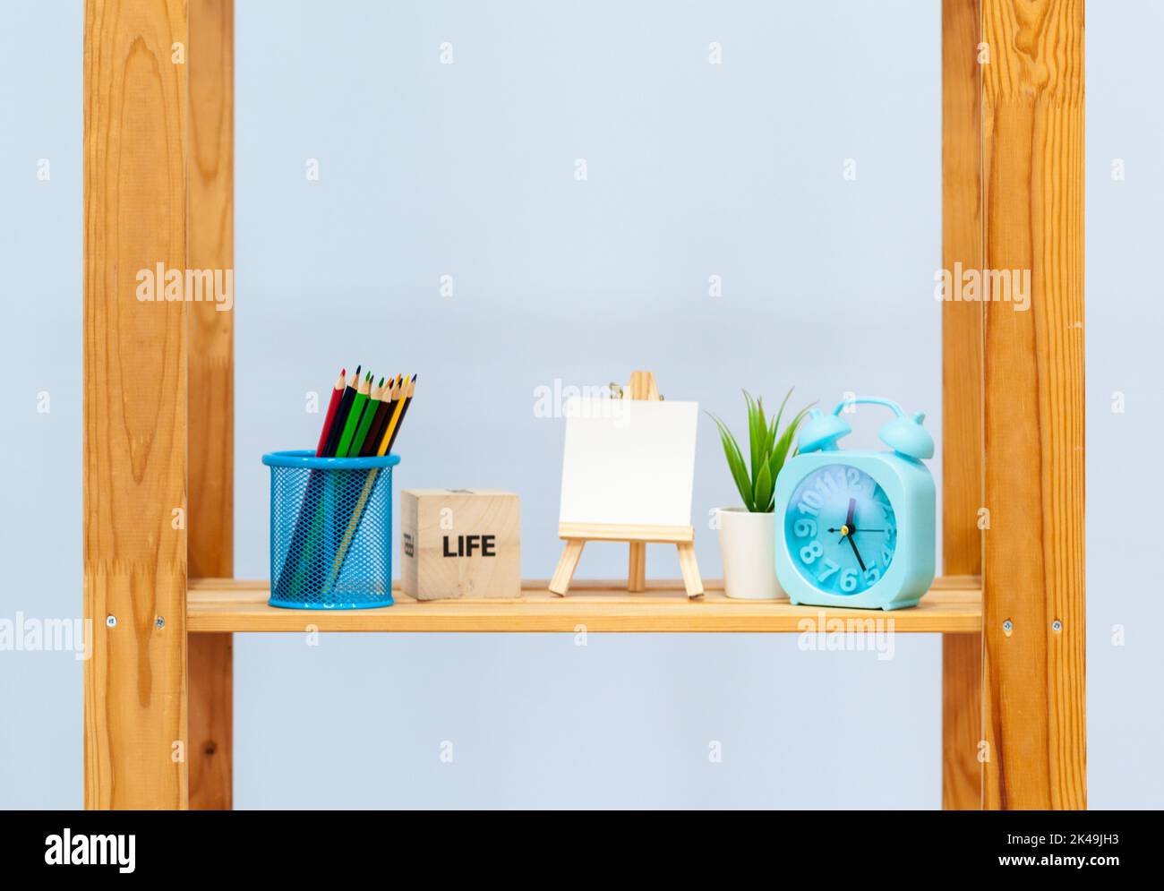 Wooden shelf with alarm clock and objects against blue background Stock ...
