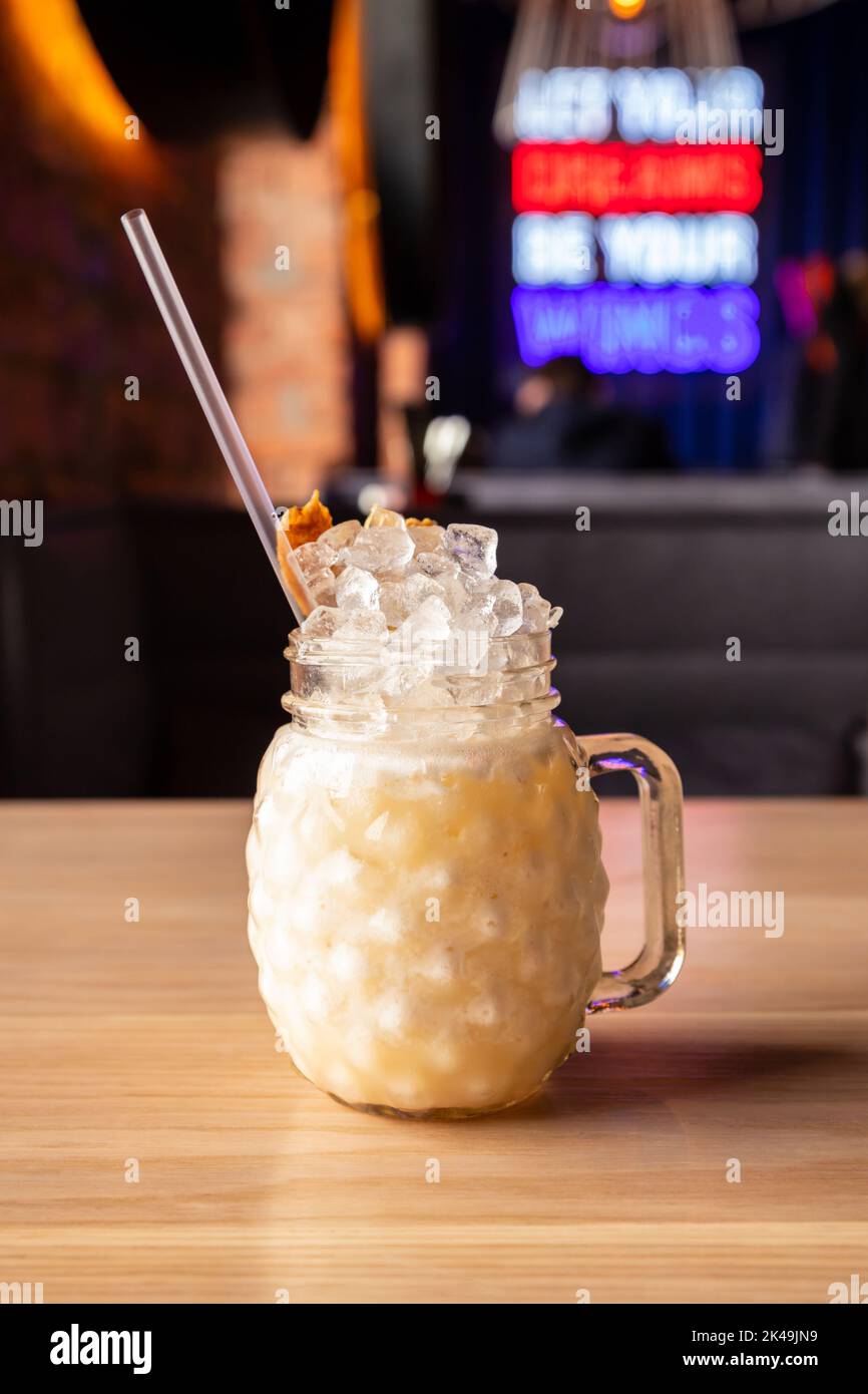 Cocktail pina colada with ice, cocktail tube and pineapple chips in ...