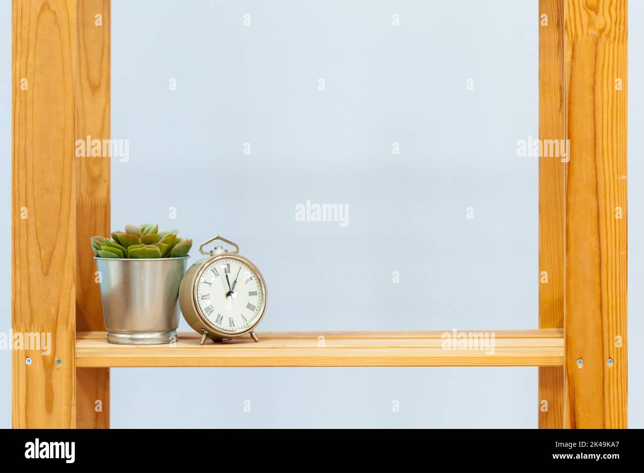 Wooden shelf with alarm clock and objects against blue background Stock ...