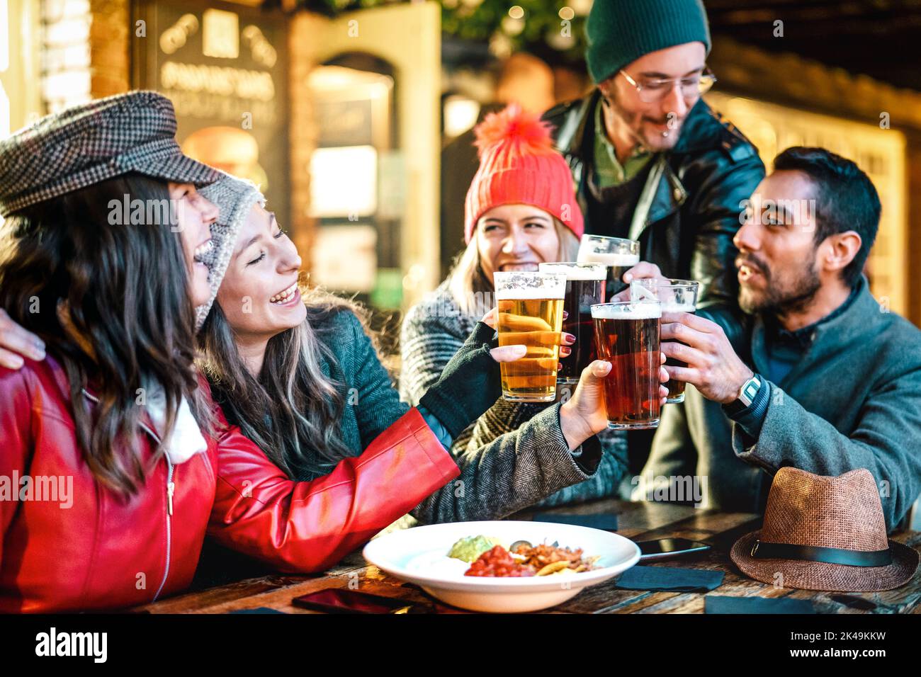 Happy multicultural friends drinking beer with nachos outdoors at night - Food and beverage ...