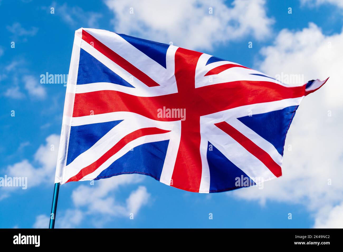 United Kingdom Flag waving on wind in blue sky Stock Photo - Alamy