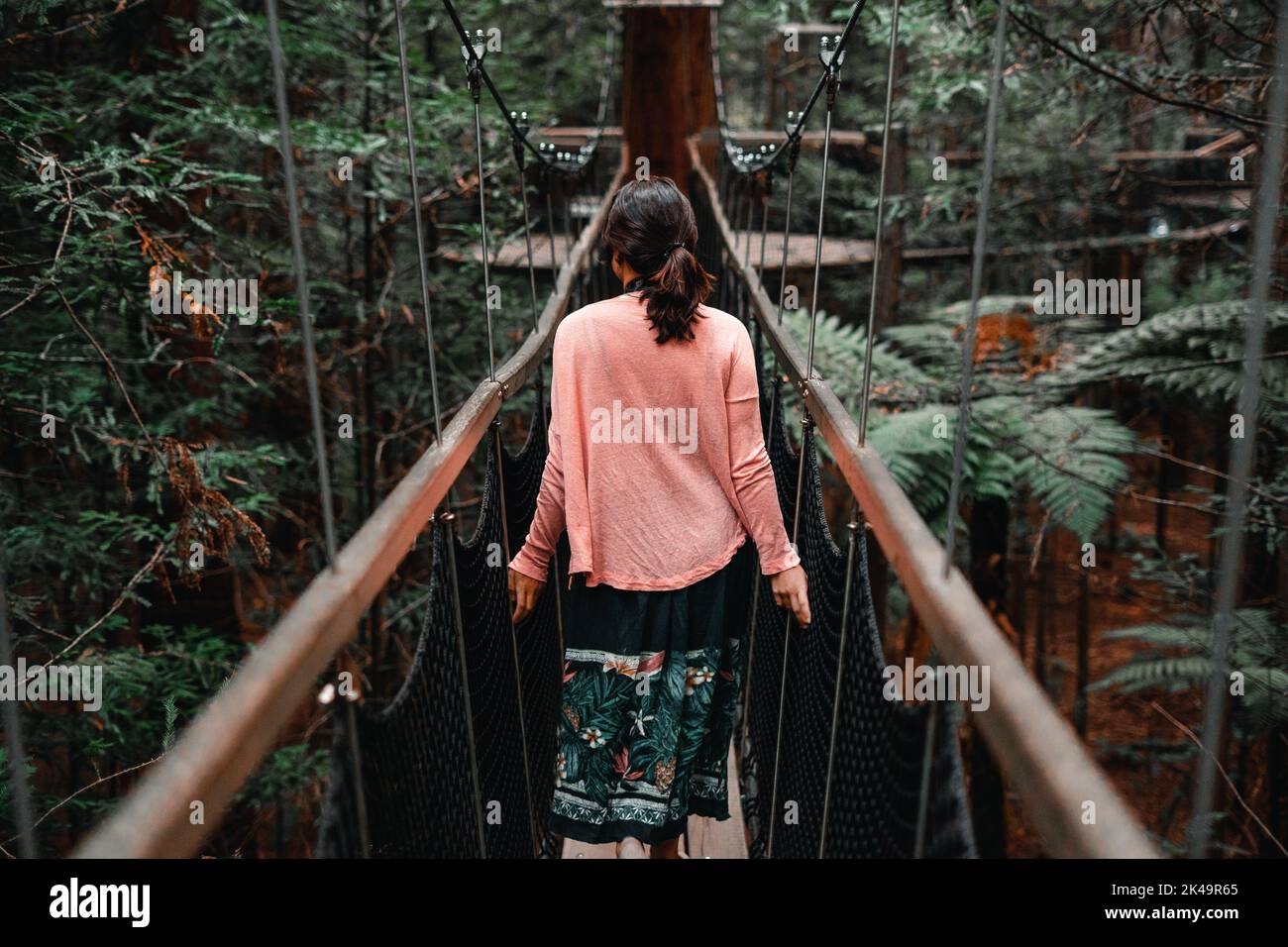 young caucasian woman leisurely strolling along a long narrow wooden ...