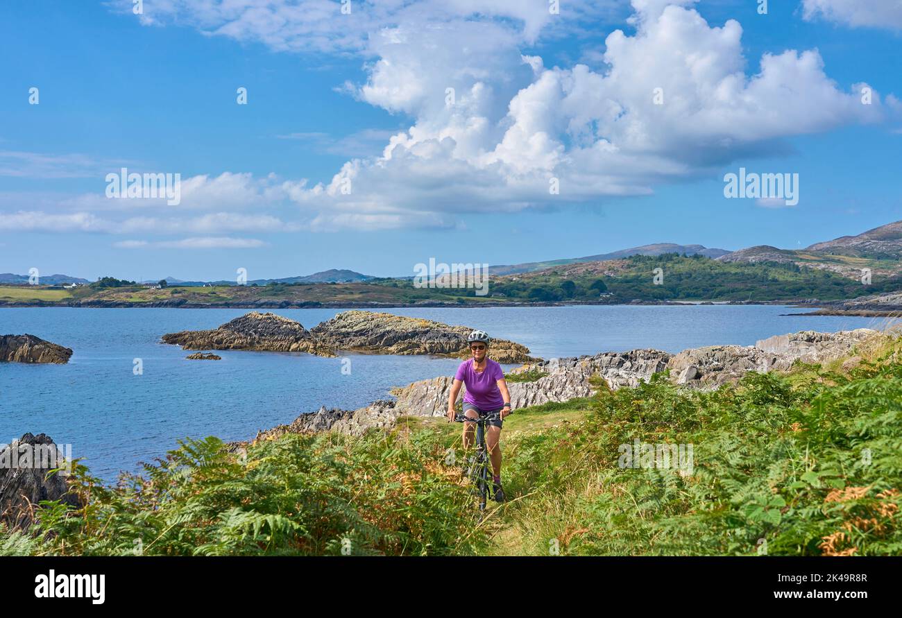 nice senior woman on mountain bike, cycling on the cliffs of Toormore ...