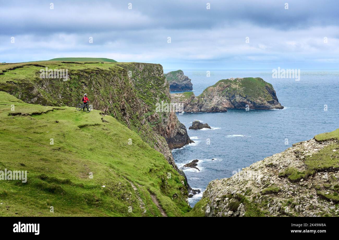nice senior woman on mountain bike, cycling on the cliffs of Cnoc an ...