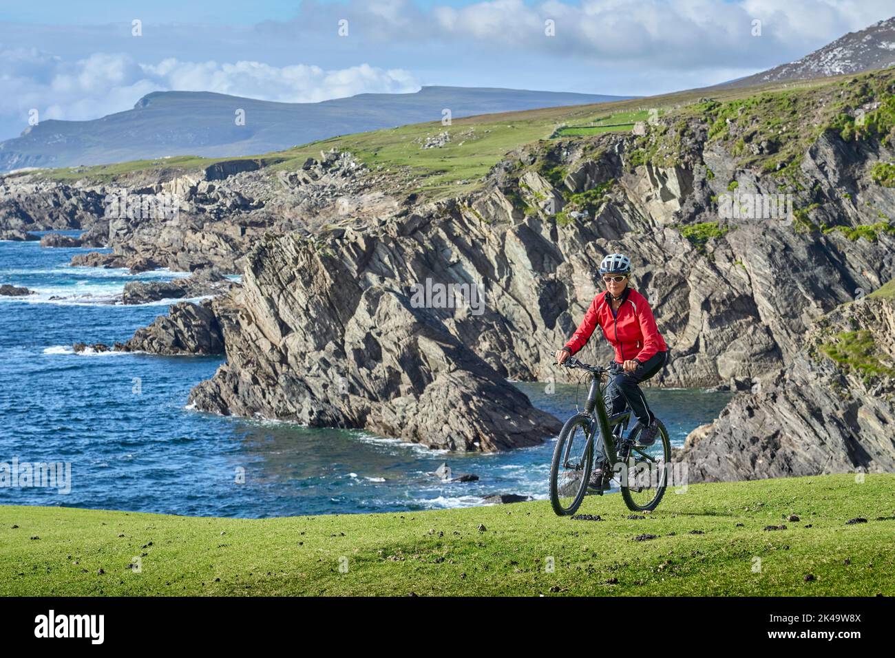 nice senior woman on mountain bike, cycling on the cliffs of Achill ...