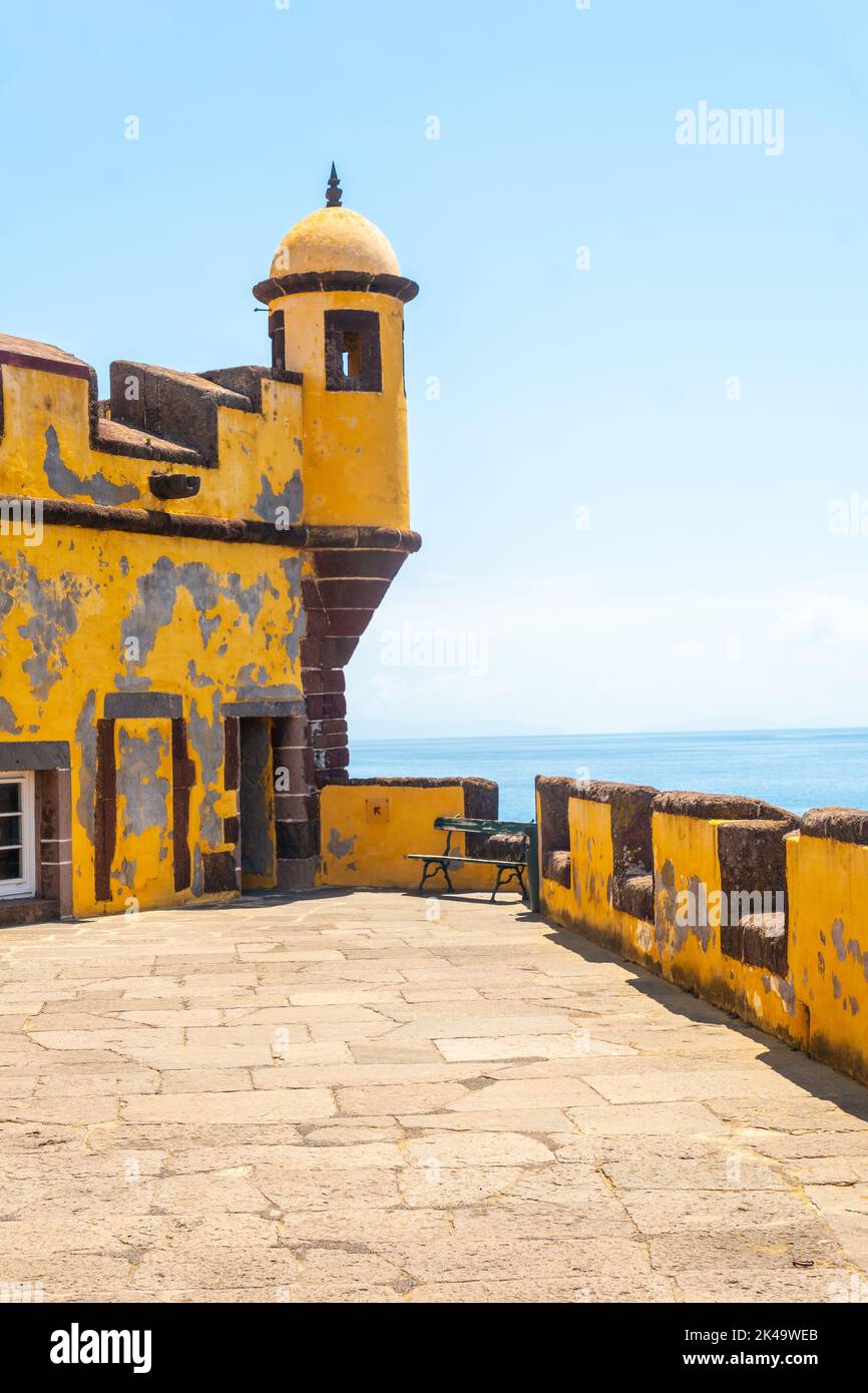 A vertical shot of the old yellow watchtower at the Forte de Sao Tiago ...