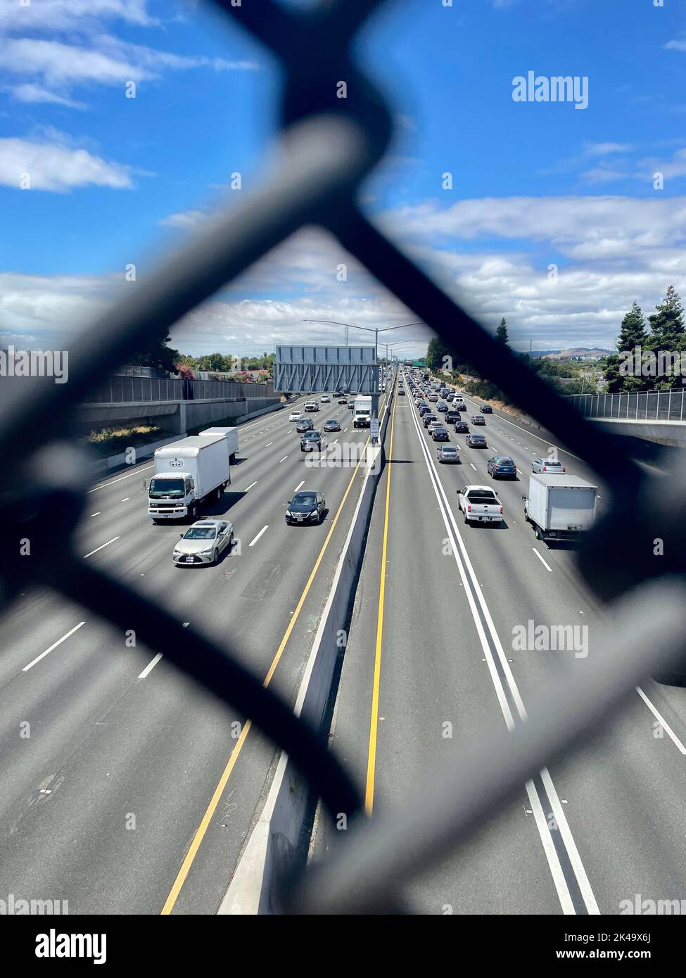A vertical view down the freeway HWY 880 through a chain link fence ...