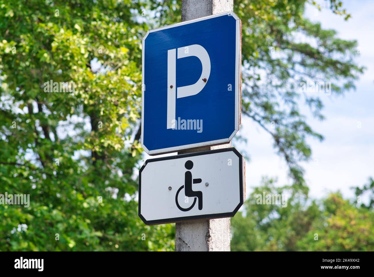 A metal pole with a blue parking sign designated for disabled drivers ...