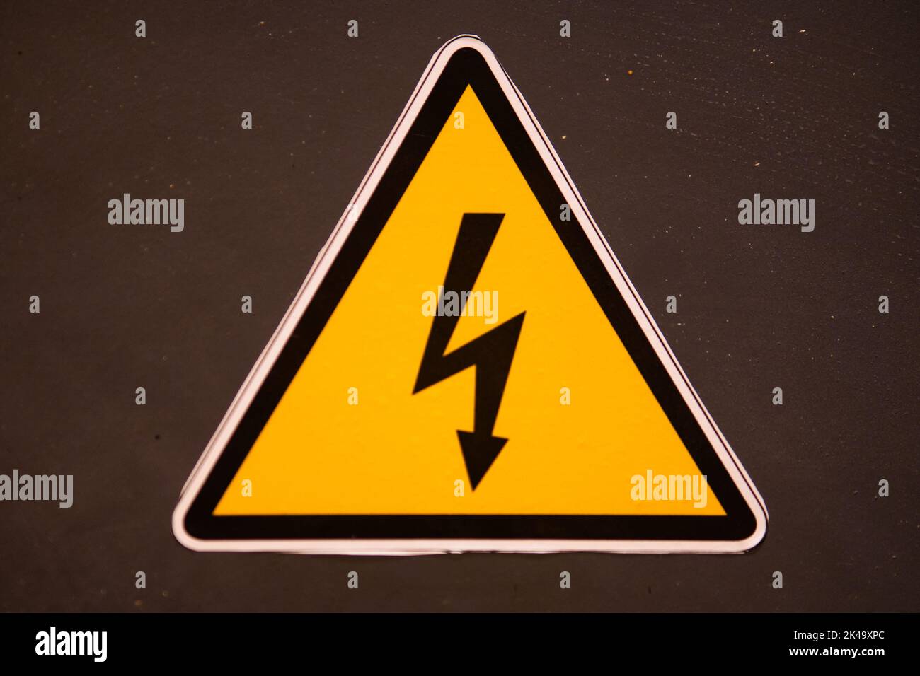 A digital render of a yellow electric shock warning sign on a brown ...
