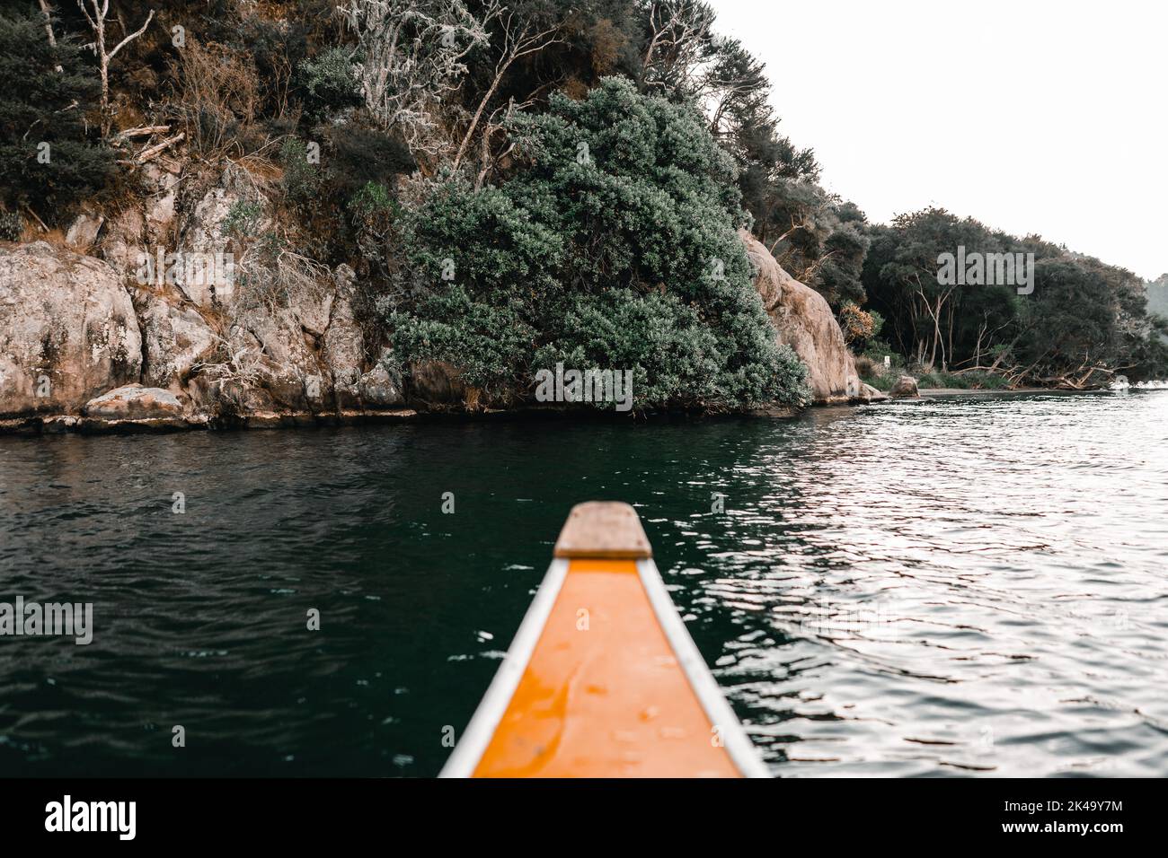prow of a canoe reaching the rocks of the lakeside near the forest ...