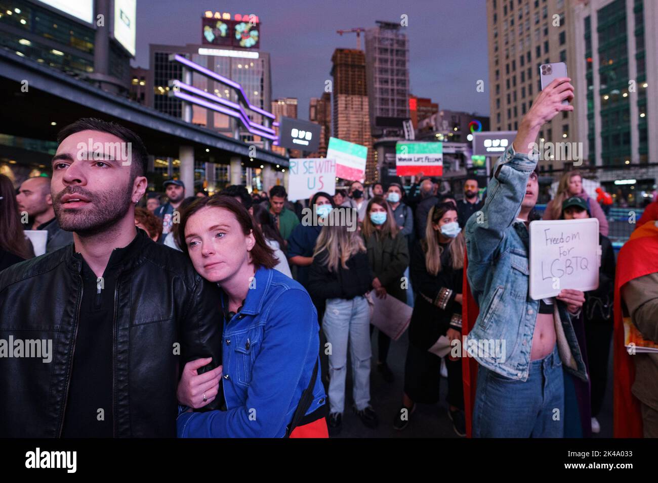 A couple embrace while watching protest organizers lead a crowd in ...