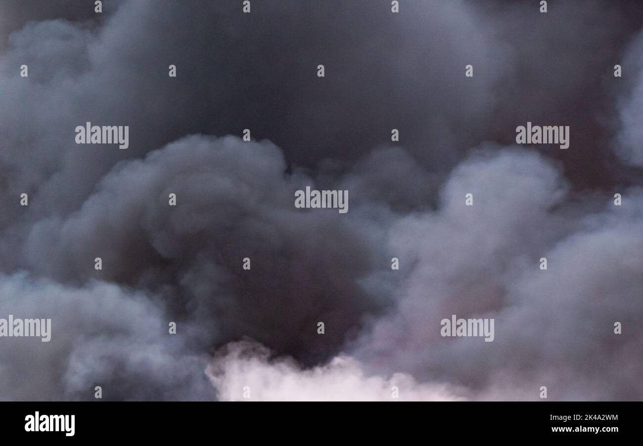 A cloud of black smoke from a fire in a building materials warehouse ...