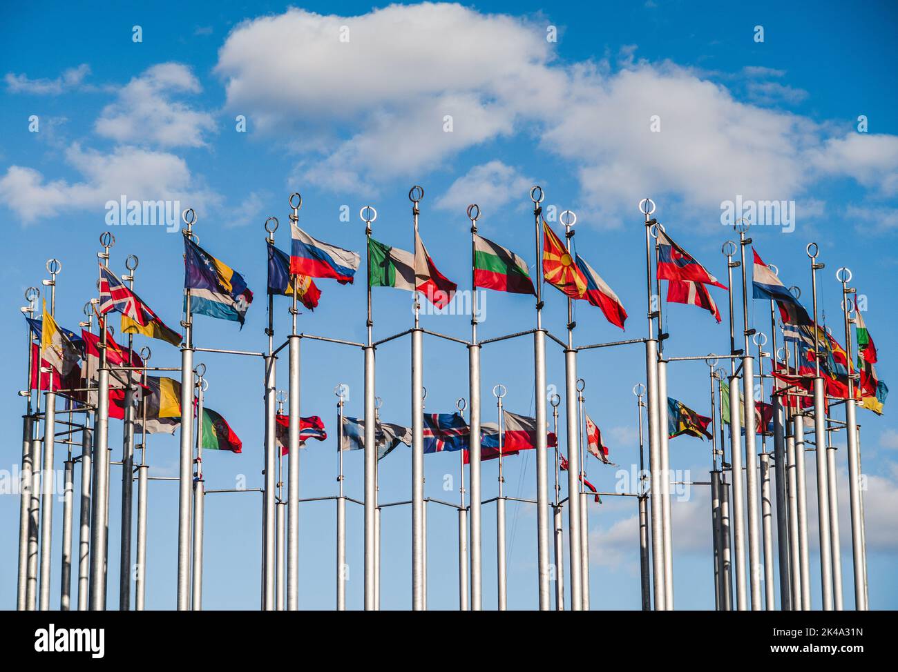 flags of the countries of the world on flagpoles against the blue sky ...
