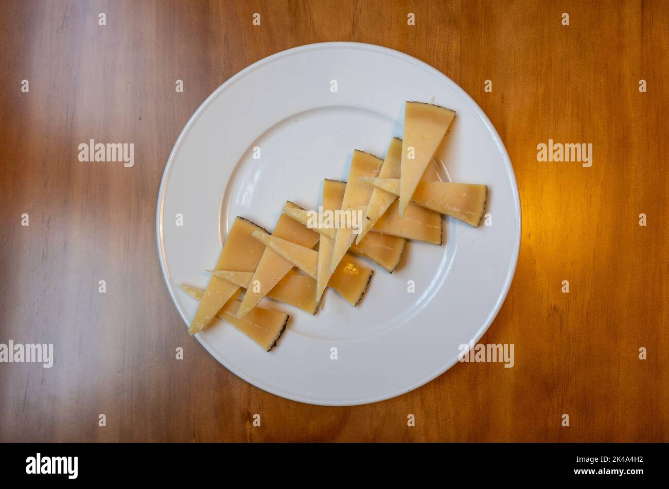 A closeup of triangle-shaped cut cheese on a plate Stock Photo - Alamy