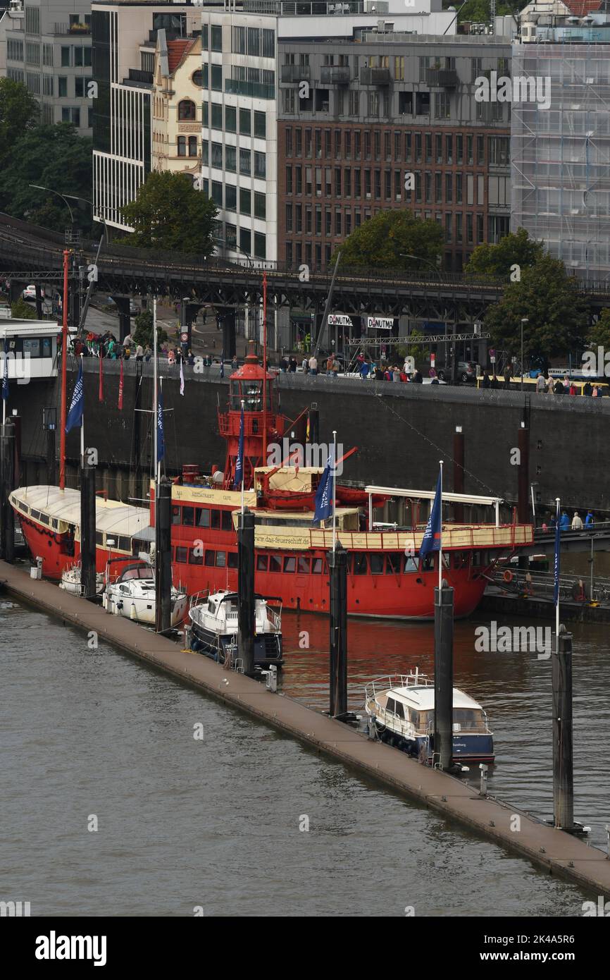 A vertical shot of a lightship with beacon in a harbor with other ships ...