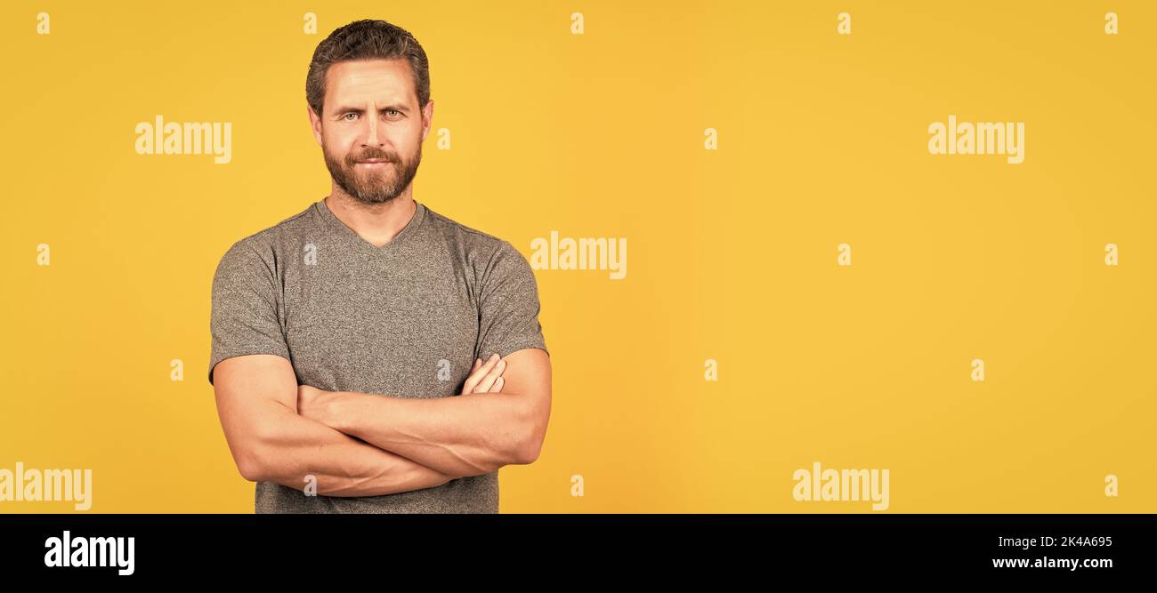 handsome mature muscular man with beard smiling on yellow background ...