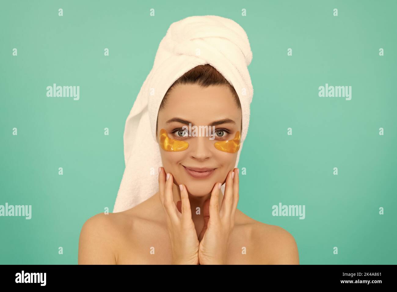 cheerful woman has collagen golden eye patches on face with towel Stock ...