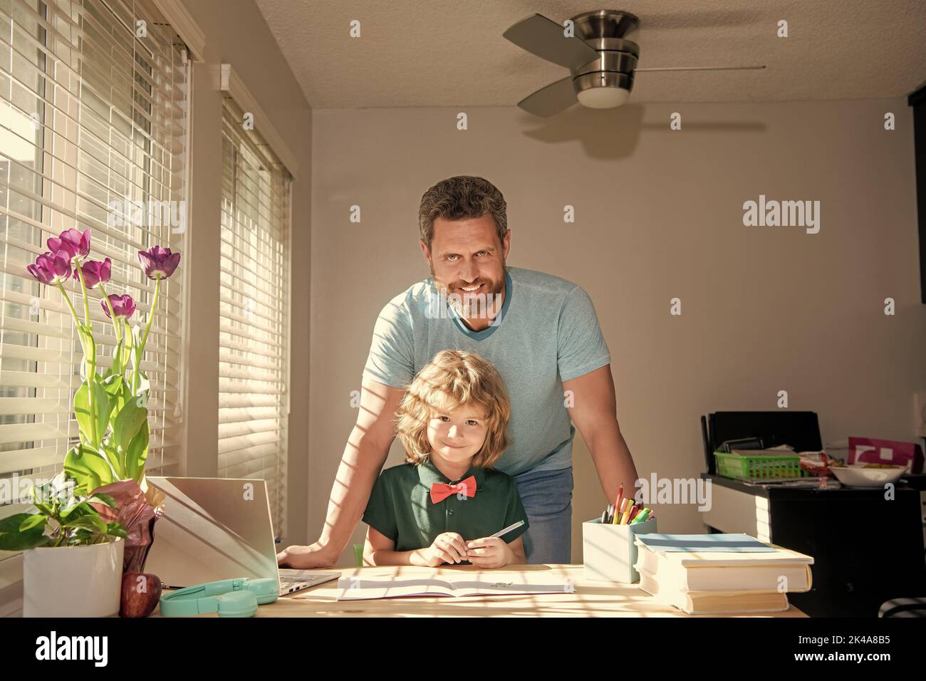 cheerful daddy writing school homework with his kid son in classroom ...