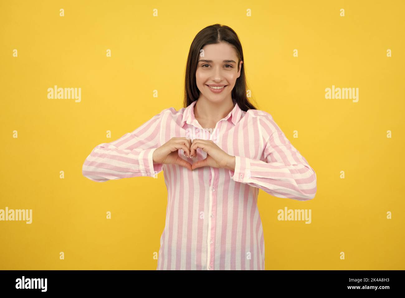 Pretty romantic young woman making a heart gesture, showing love and ...