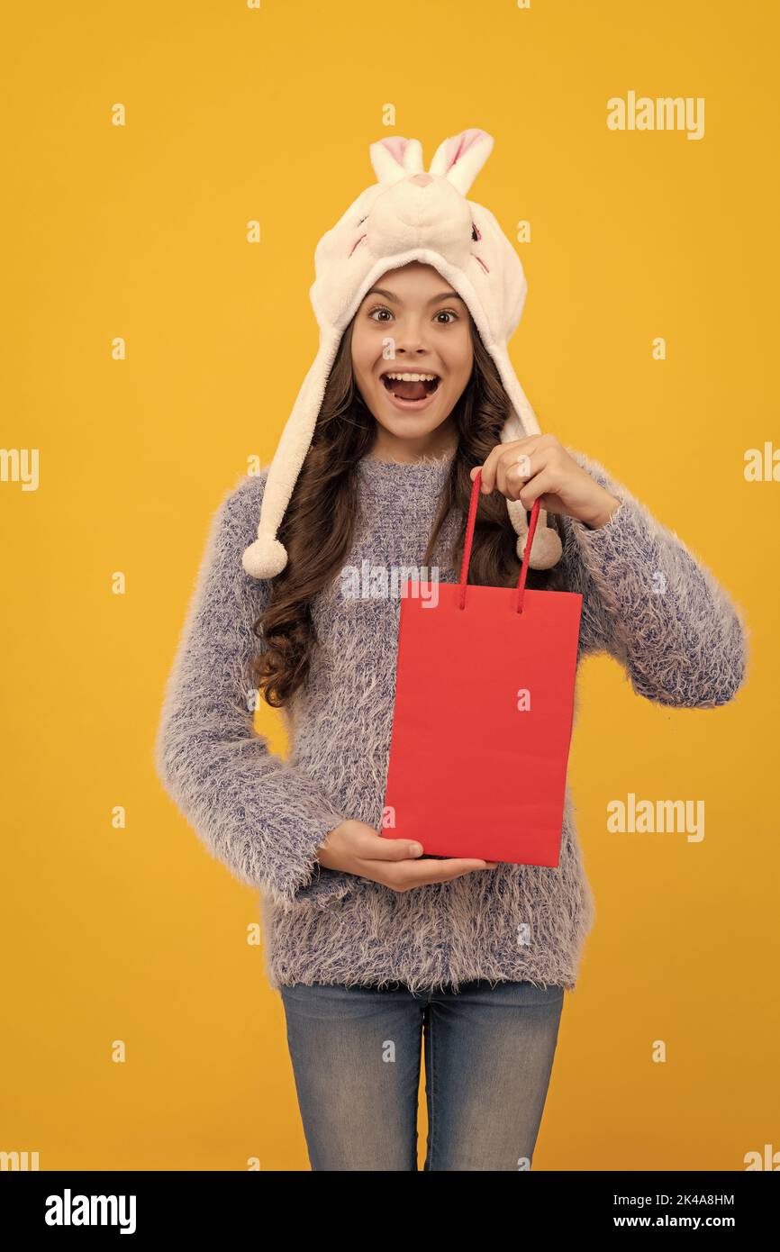 happy kid long hair in hat hold pack on yellow background, new year ...
