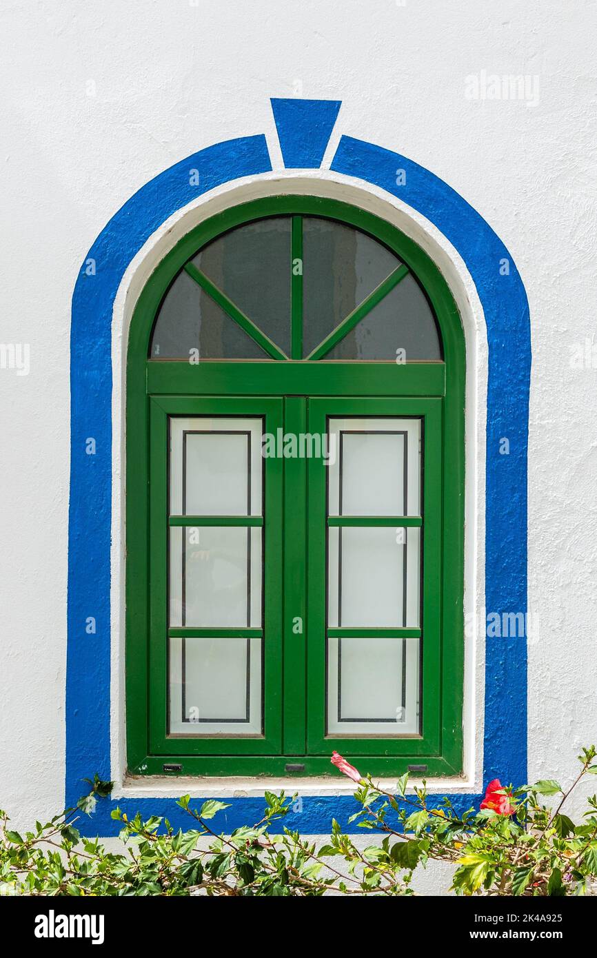 A vertical shot of a decorative arched green window with a blue outline ...