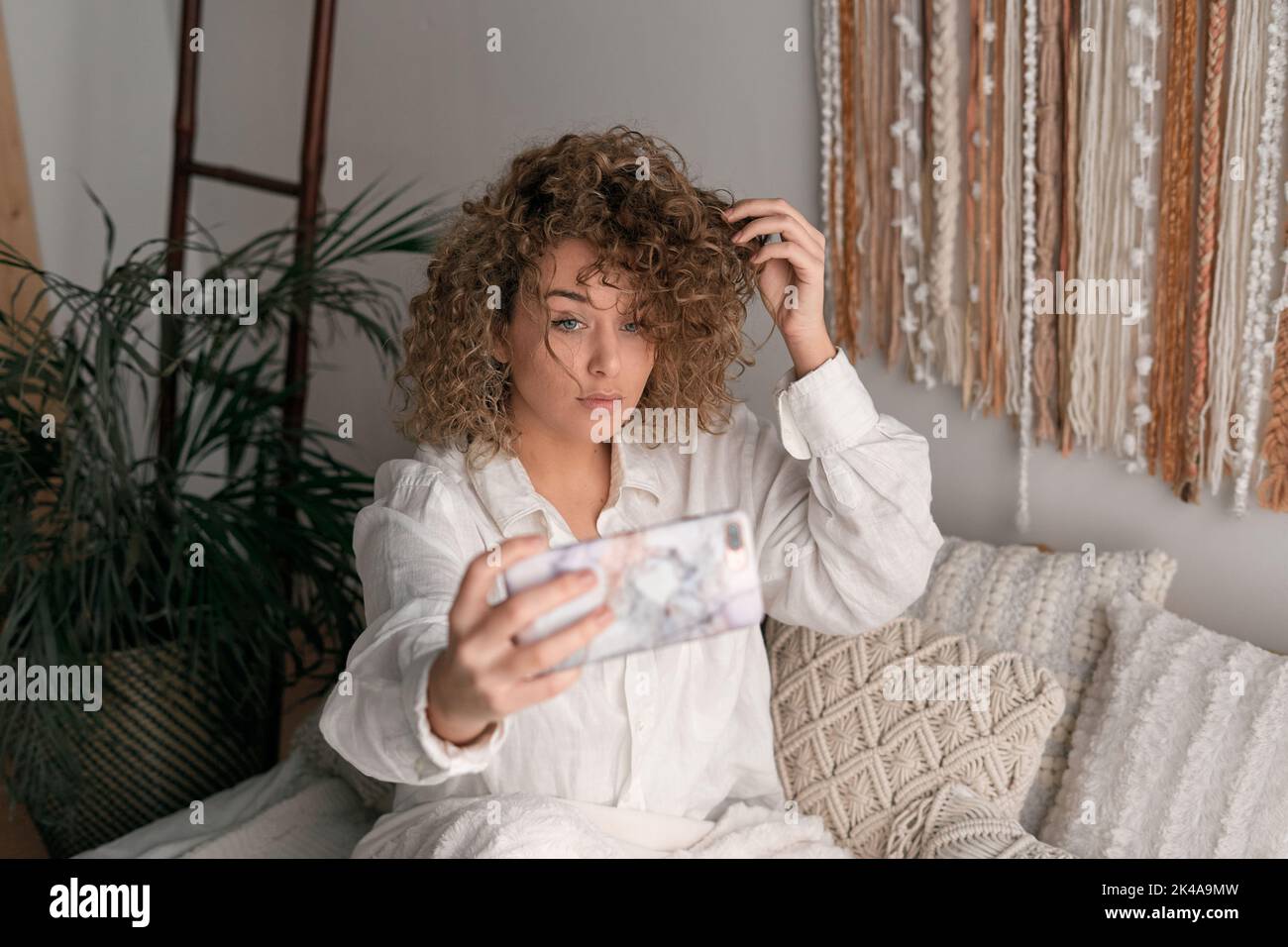 Charming woman taking selfie on bed Stock Photo - Alamy