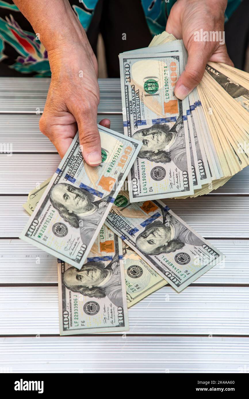 Hand counting USD Currency Hundred Dollar Bills on an Aluminum Table ...