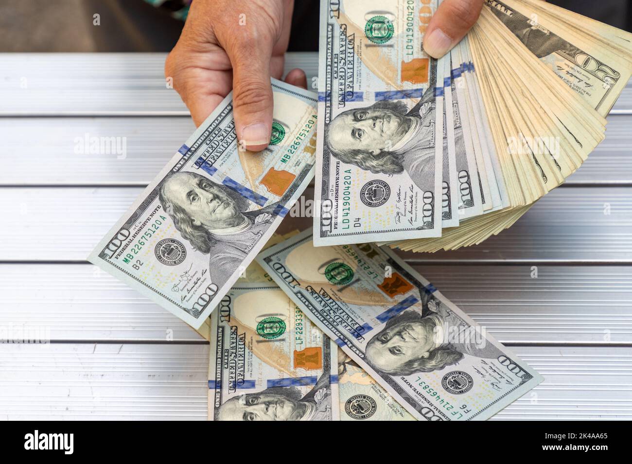 Hand counting USD Currency Hundred Dollar Bills on an Aluminum Table ...