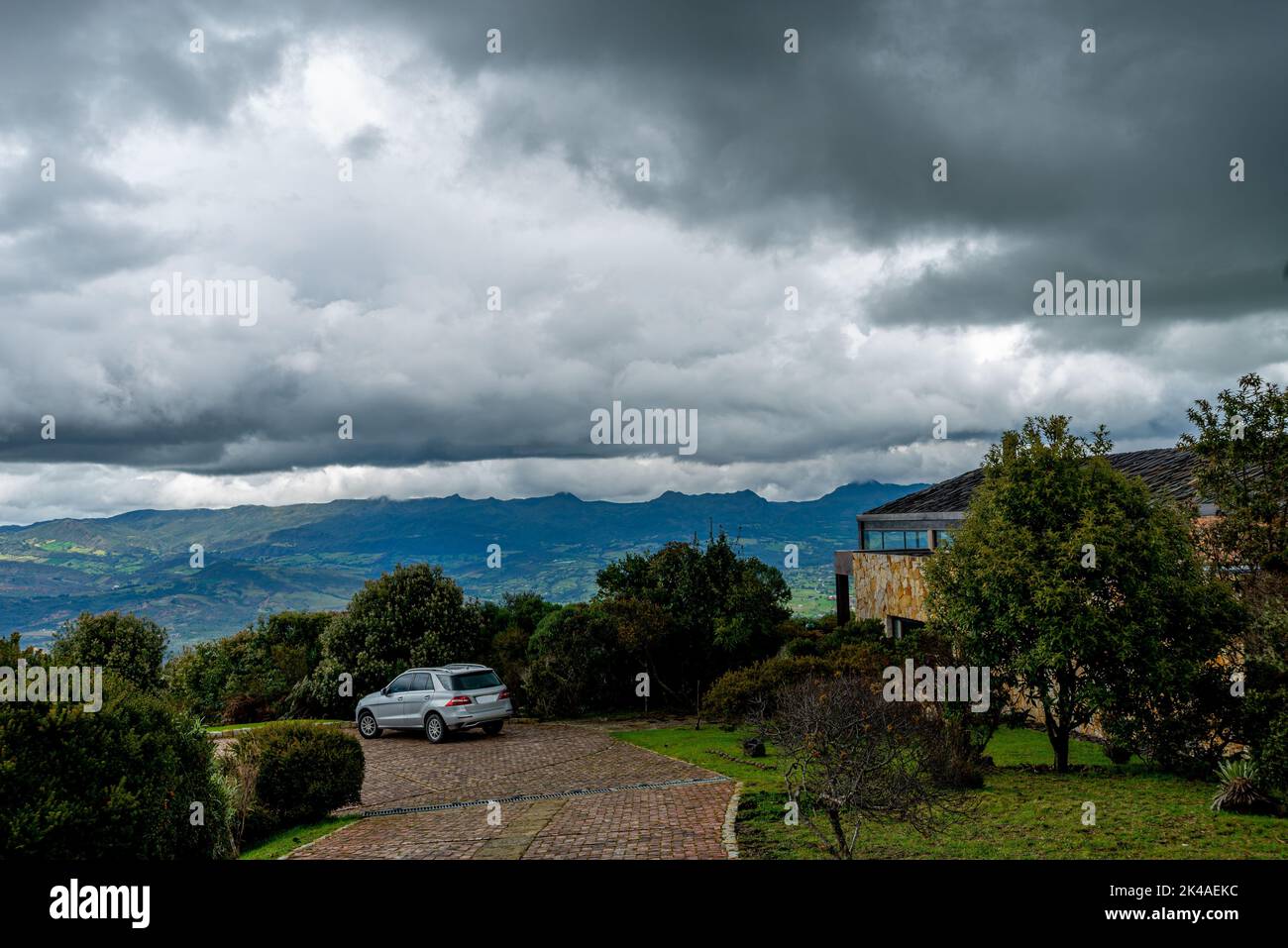 A scenic view of a house high in the mountains on a cloudy rainy day ...