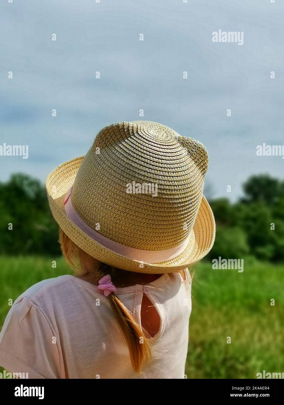 A vertical rear view of a girl with a straw hat Stock Photo - Alamy
