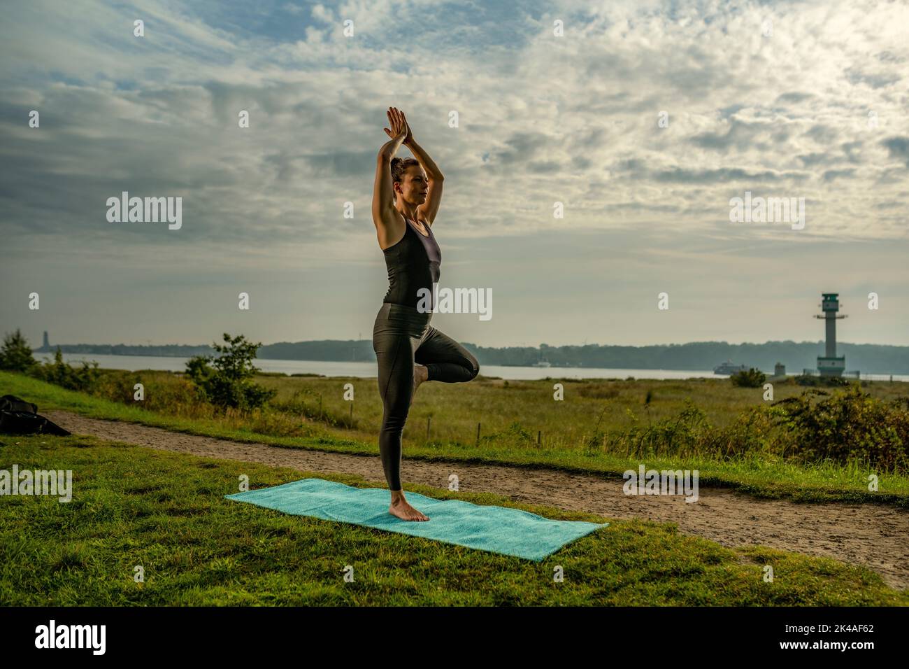 a woman is doing the tree pose at the beach Stock Photo - Alamy
