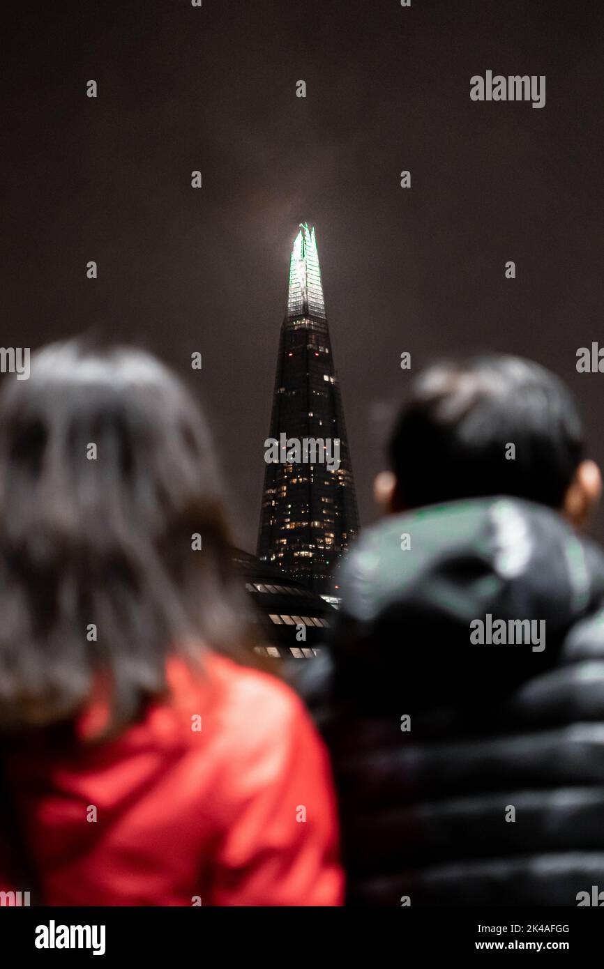 A low angle shot of the Shard in London behind tourists viewing the ...
