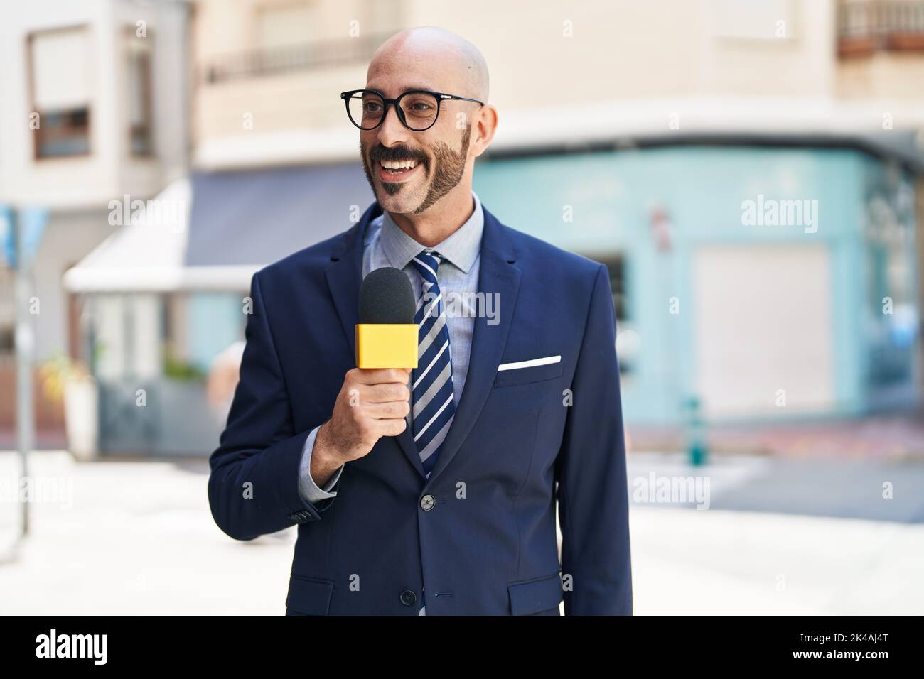 Young hispanic man reporter working using microphone at street Stock ...