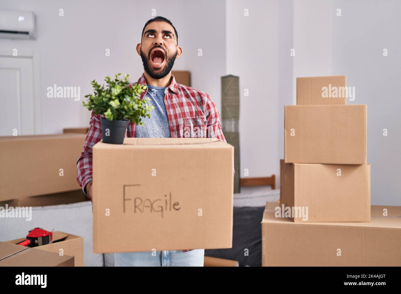 Middle east man with beard moving to a new home holding cardboard box ...