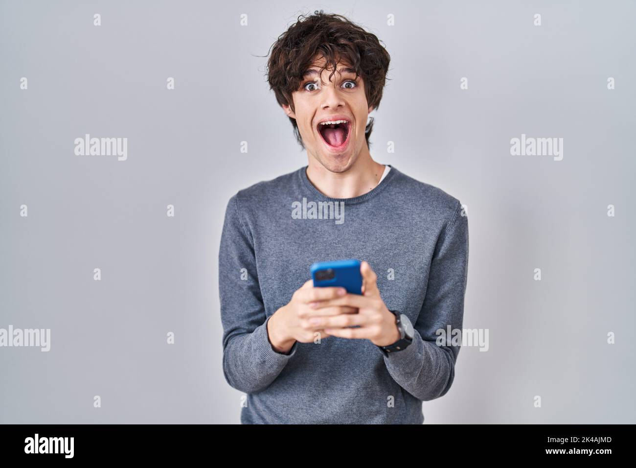 Young man using smartphone typing a message celebrating crazy and ...