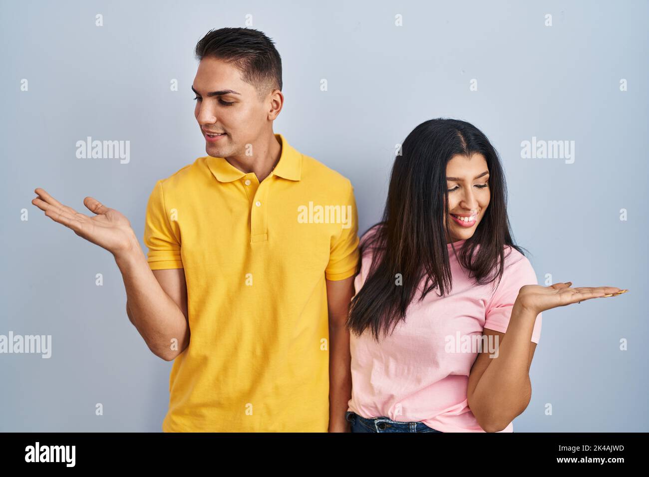 Young couple standing over isolated background smiling showing both ...